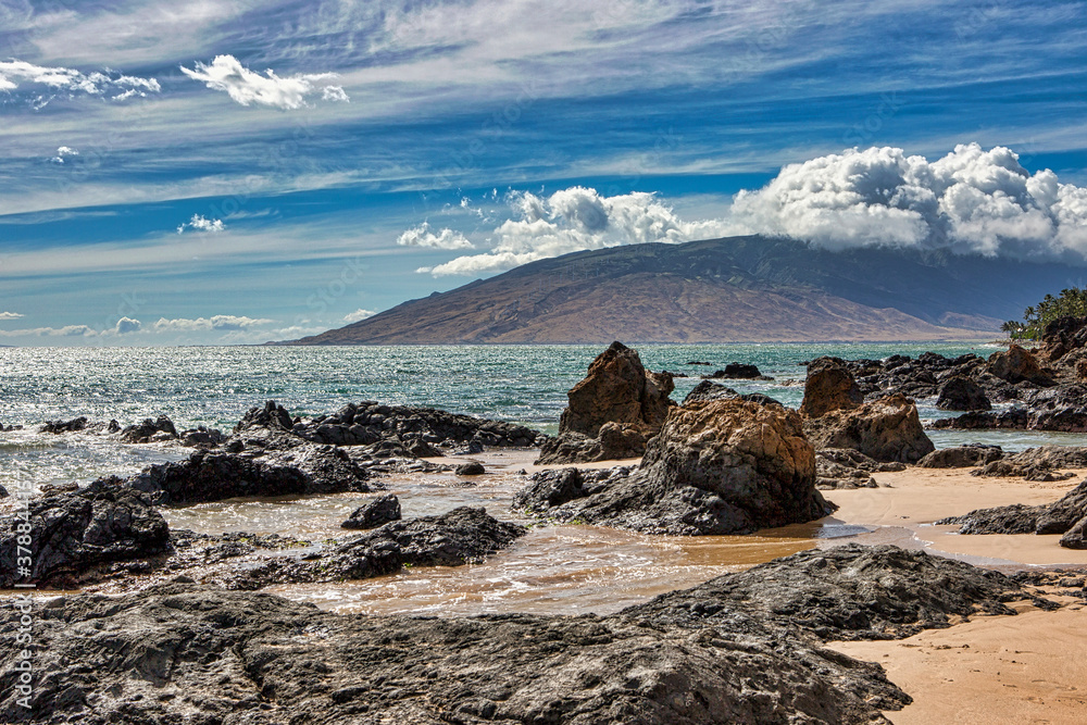 Lava rock and sand at Charley Young Beach with the West Maui Mountains ...