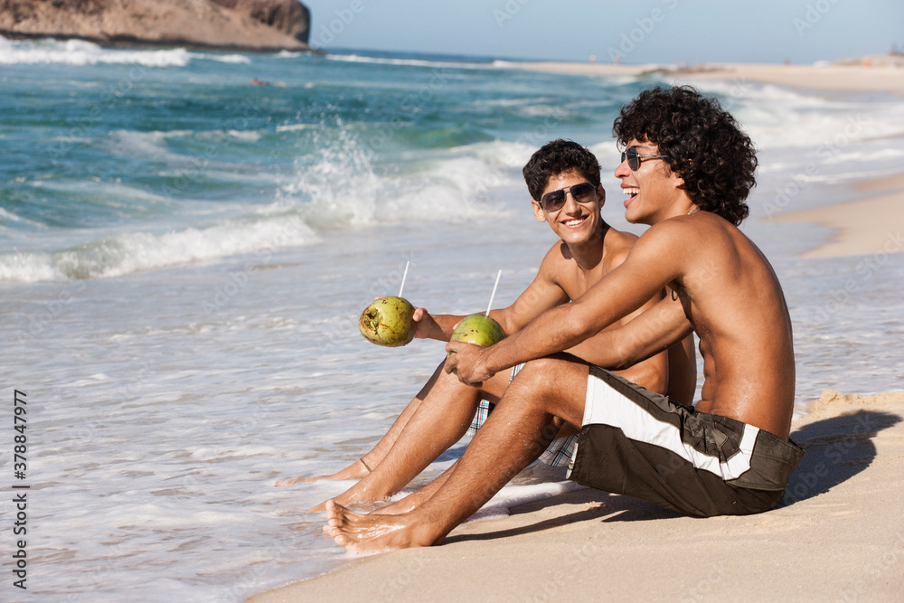 Men drinking from coconuts on beach Stock Photo | Adobe Stock