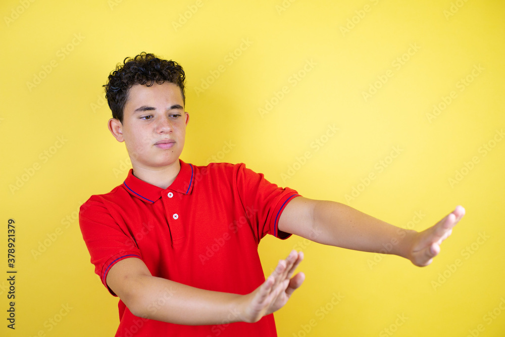 Beautiful teenager boy over isolated yellow background afraid and ...