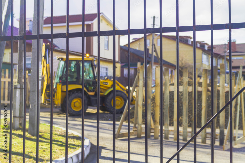 Construction of a new house using a yellow bulldozer. Fence around the ...