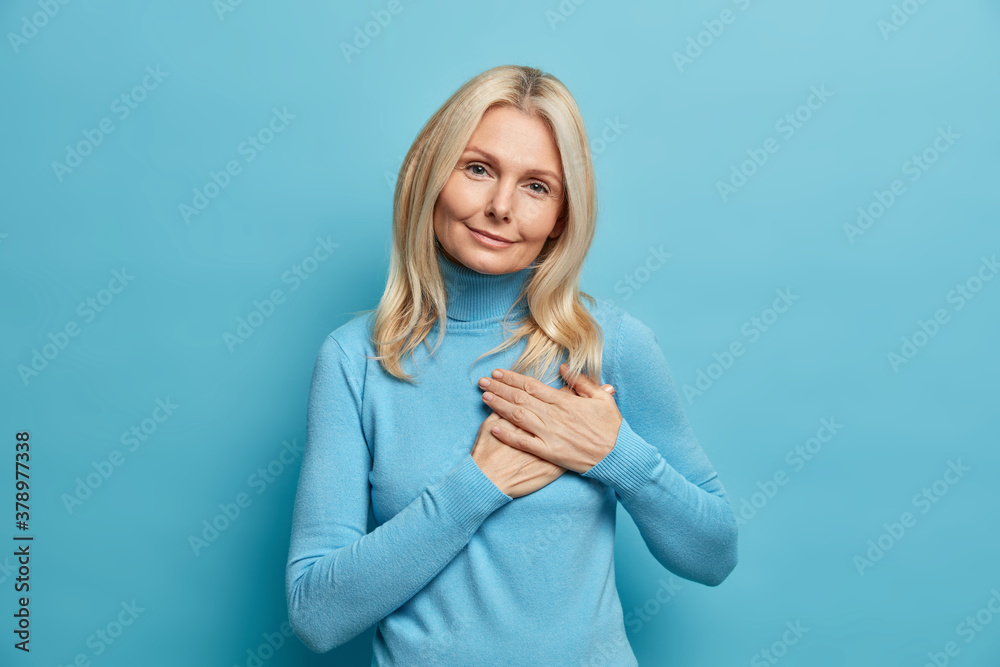 Beautiful blonde adult woman makes gratitude gesture presses hands to ...