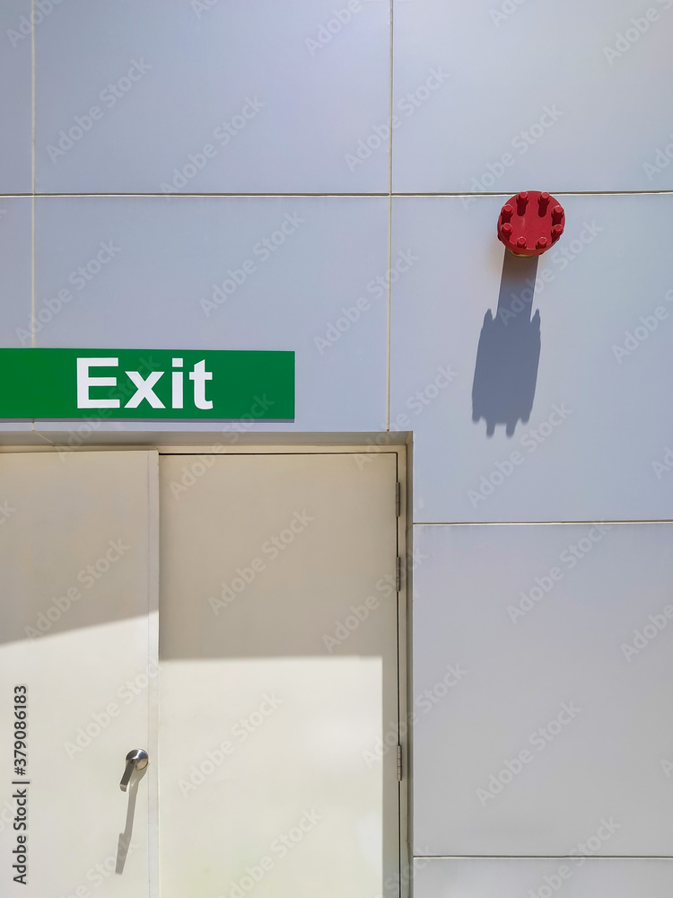 Green emergency exit sign over white door with red fire hydrant ...