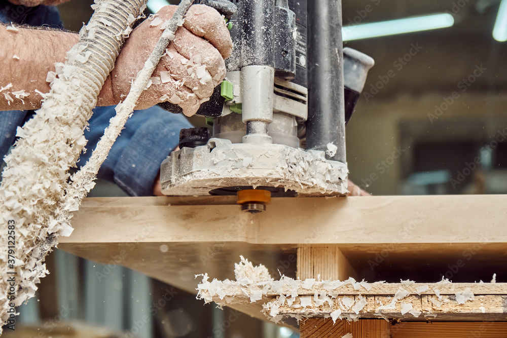 Carpenter with hand electric router machine at work. Milling process of ...