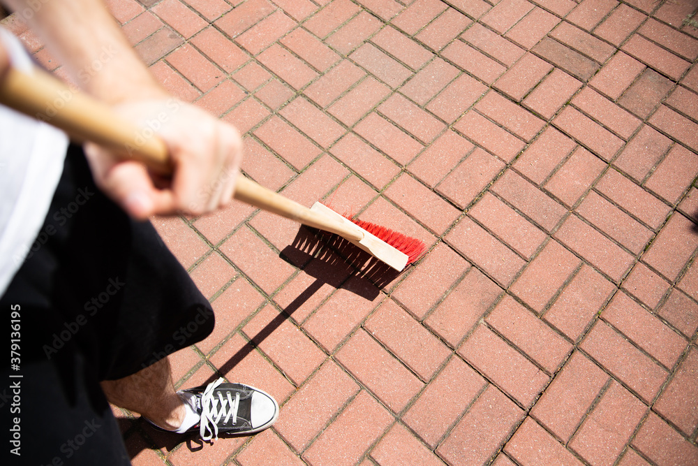 Sweeping a driveway, stone paving with a broom. Stock Photo | Adobe Stock