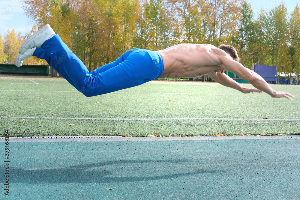 middle aged man doing jumping push-ups on a stadium. muscular man ...