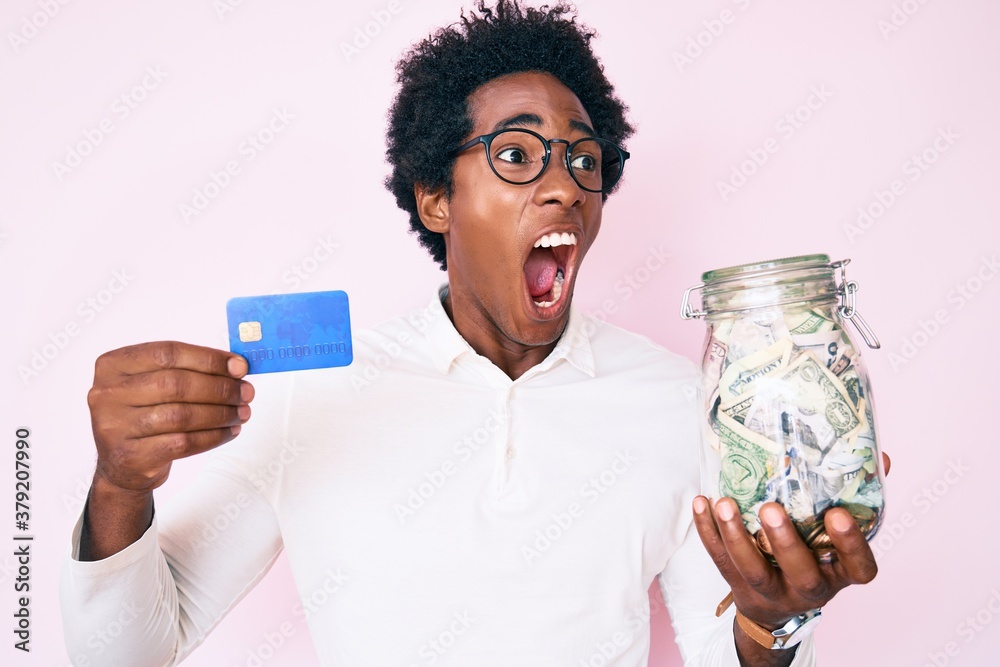 Handsome african american man with afro hair holding credit car and jar ...