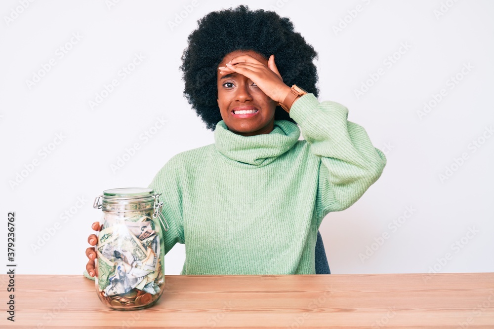Young african american woman holding jar with savings stressed and ...