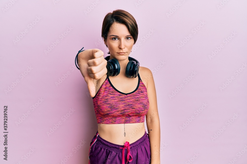 Young brunette woman with short hair wearing sportswear and headphones ...