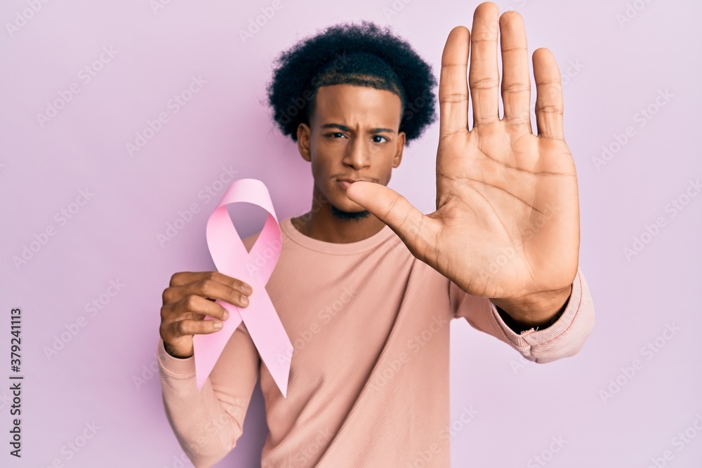 African american man with afro hair holding pink cancer ribbon with ...