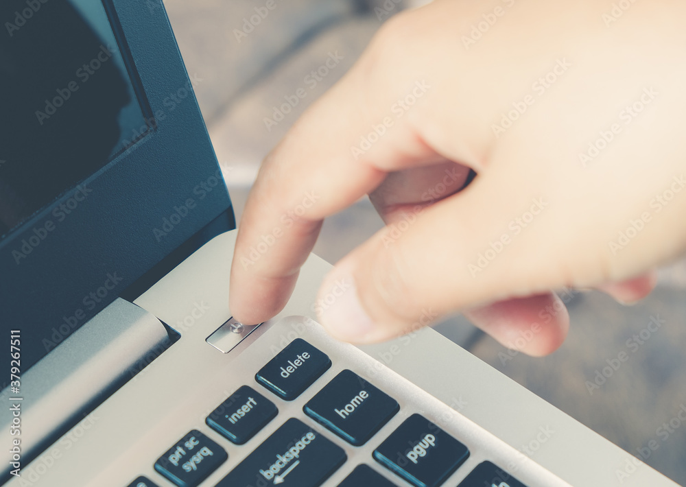 Finger pushing start power button on the laptop computer. Press turn ...