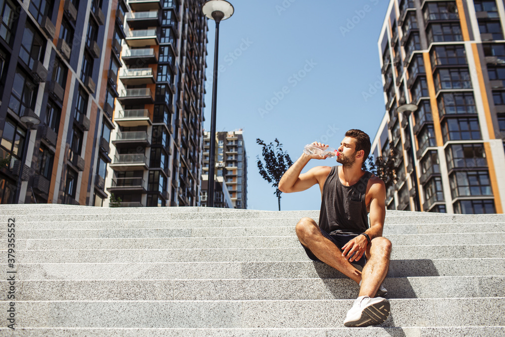 Young man exercising outside. Picture of athletist drinking water ad ...