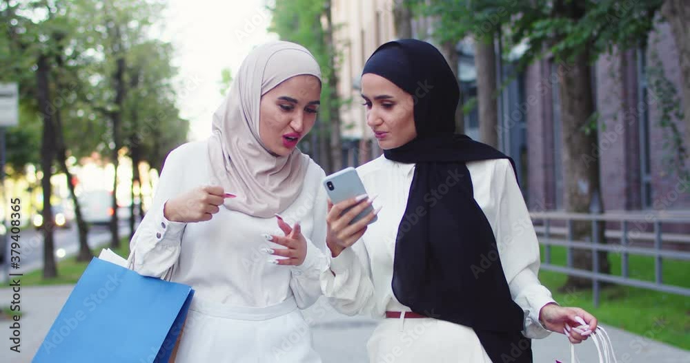 Middle plan of two Arabic women in traditional headscarves making ...