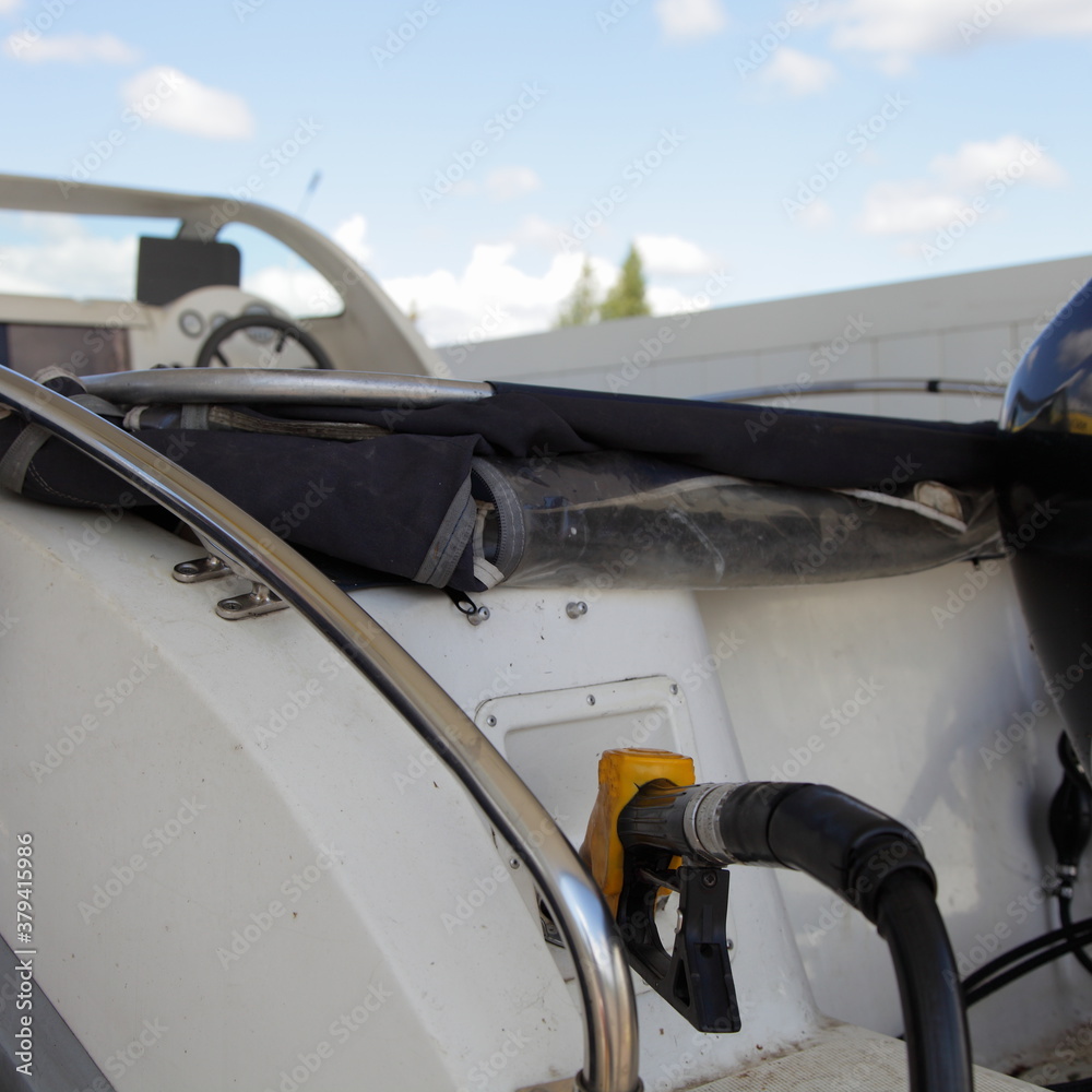 Motor boat fueling, fuel gun with hose in transom filler cap on blue ...