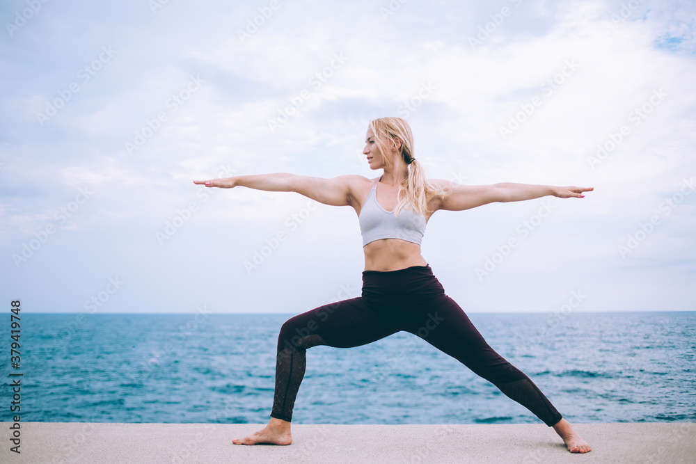 Caucasian female yogi practicing Virabhadrasana during morning workout ...