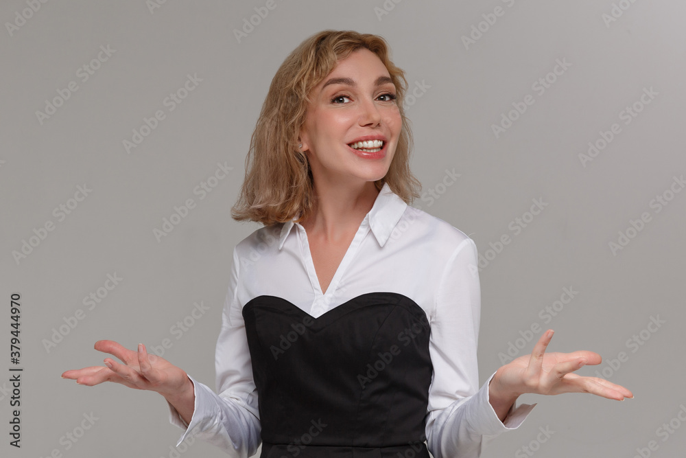 Carefree happy clueless young woman shrugging with hands spread aside ...