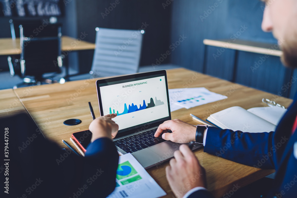 Cropped image of male and female experts browsing business infographics ...