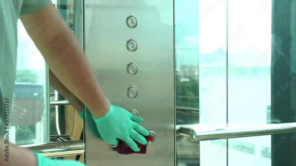 Man staff hand using wet wipe cleaning an elevator push button control ...
