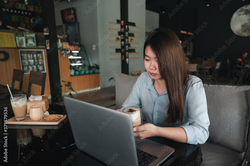 A female Asian office worker of Thai descent is typing and working with ...