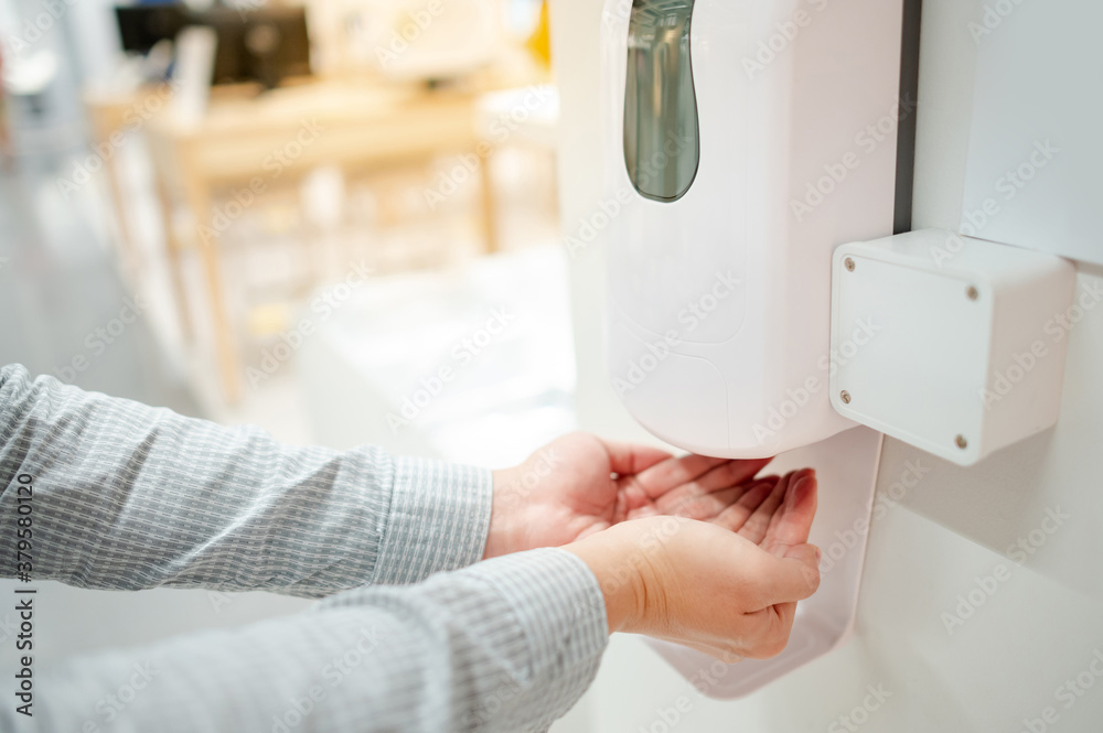 Male hands using automatic alcohol dispenser for cleaning hand in ...