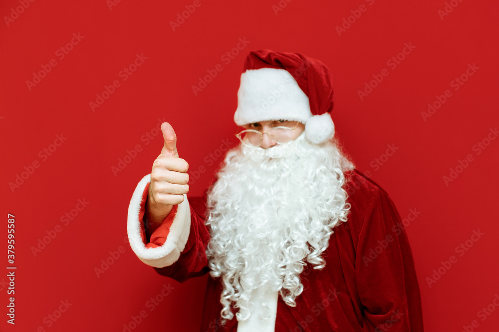 American Santa Claus stands on a red background, shows thumb up and ...