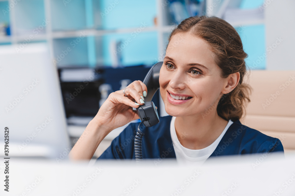 Young female doctor practitioner working at reception desk while ...
