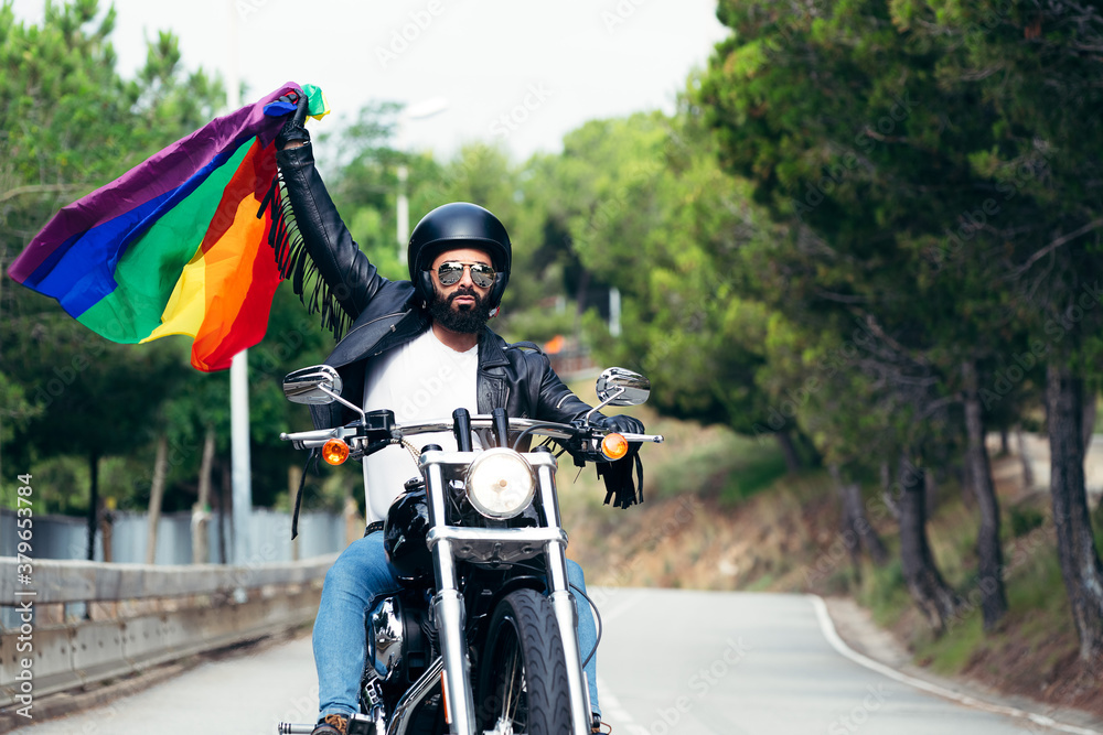 man riding his motorcycle flying the rainbow flag Stock Photo | Adobe Stock