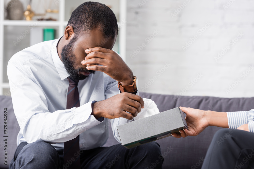stressed african american man covering eyes with hand while taking ...