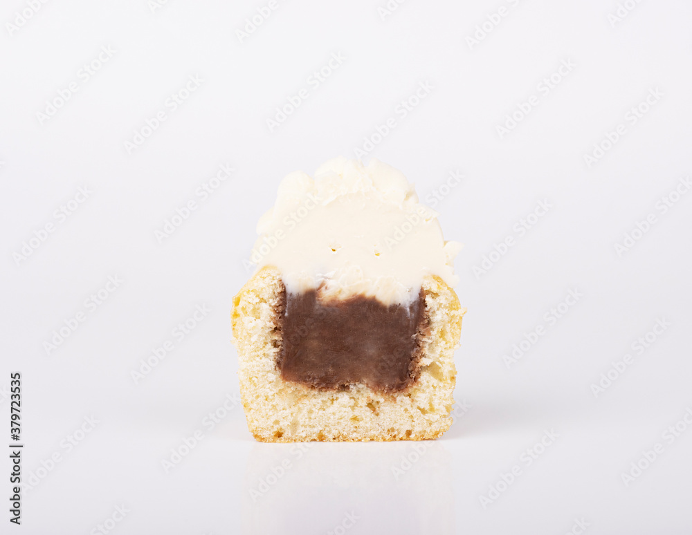 The cupcake is cut in half, with a chocolate filling and white vanilla ...
