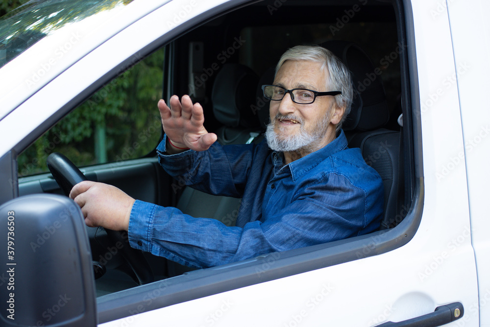 Happy mature grey haired man in eyeglasses and denim shirt driving ...