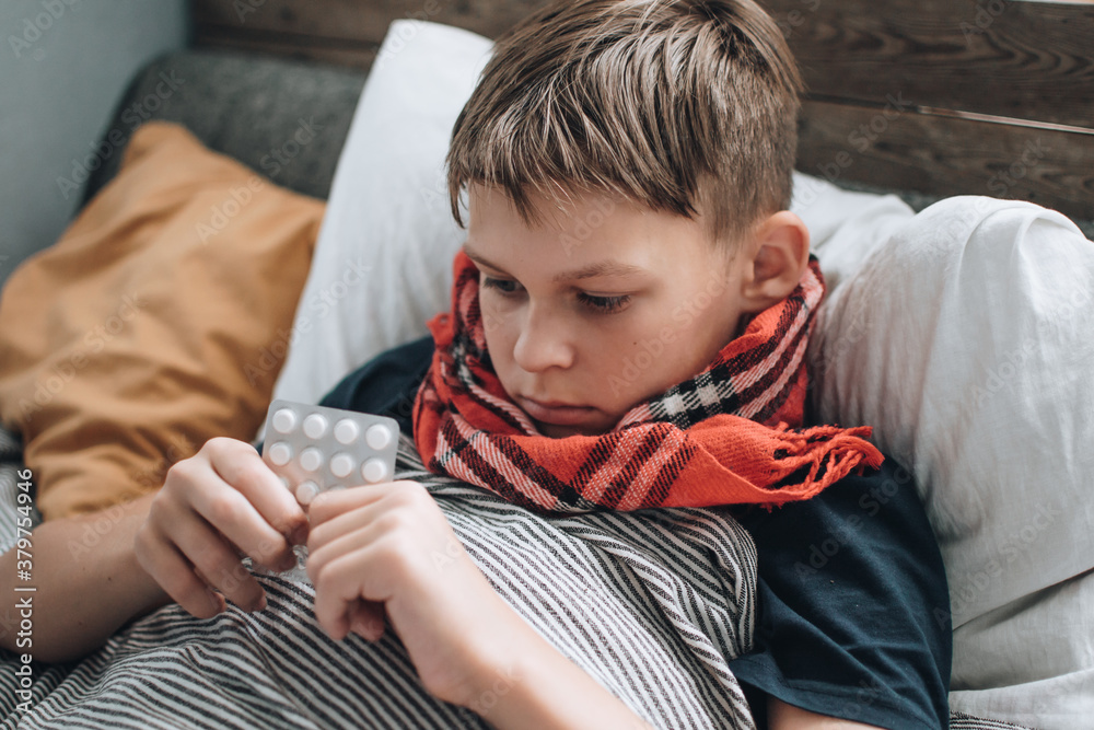Sick teenage boy with flu is sneezing and coughing on the bed ...