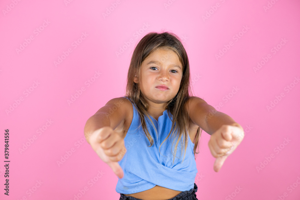 Young beautiful child girl over isolated pink background with angry ...