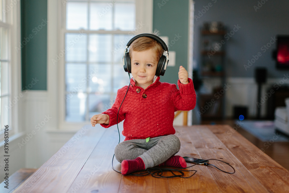 Cute young boy sitting on a table listening to music headphones Stock ...