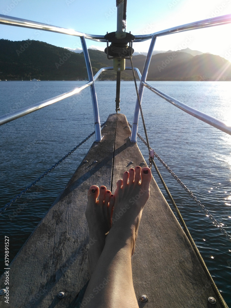 Bare female feet at the nose of yacht with sea and hills around Stock ...