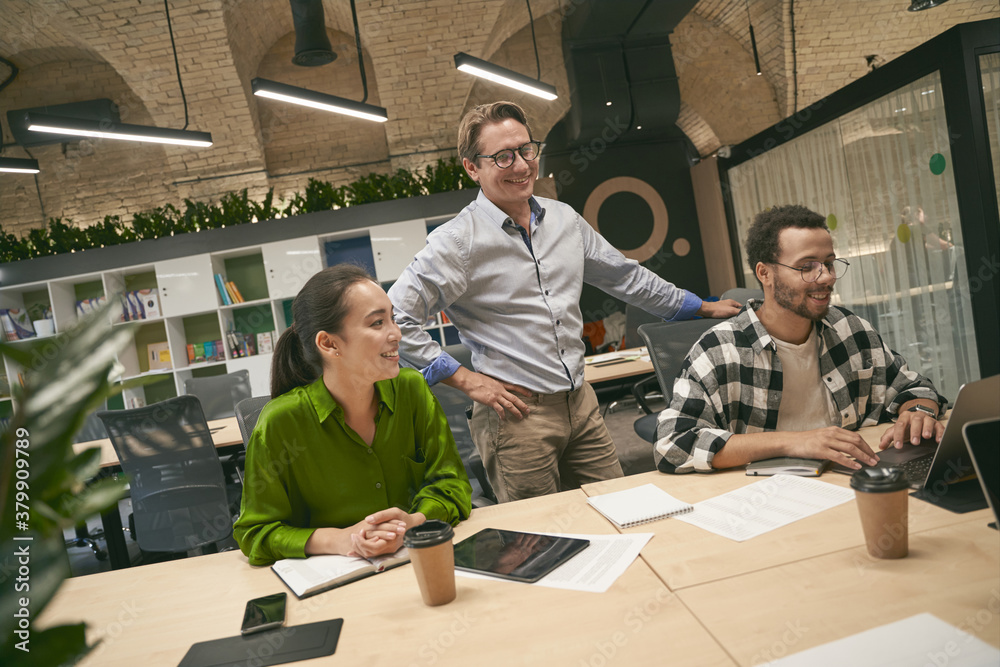 Three young happy multiracial colleagues working together in the modern ...