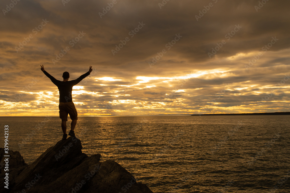Back view of a man standing on a rock and facing the St Lawrence river ...