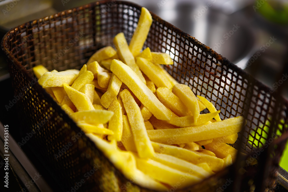 Raw uncooked french fries in deep fryer oven in fast food restaurant ...