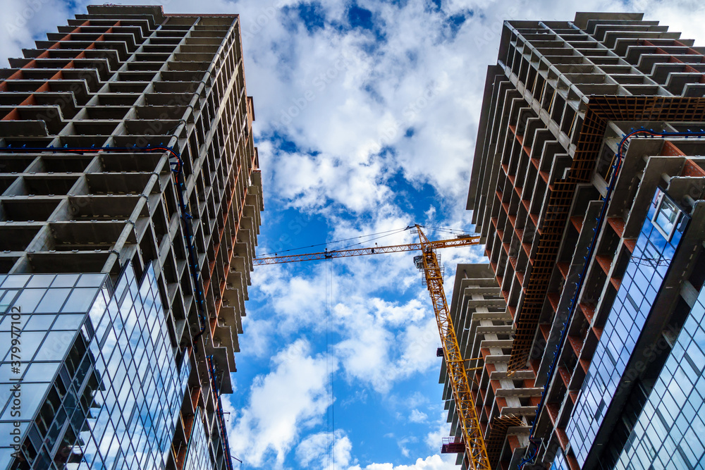 Two new high-rise buildings & working tower crane. Scenic cloudy sky is ...