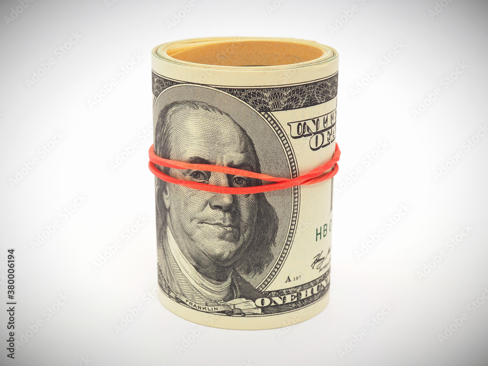 A bundle of old-style 100 dollar bills is rolled up, tied with an ...