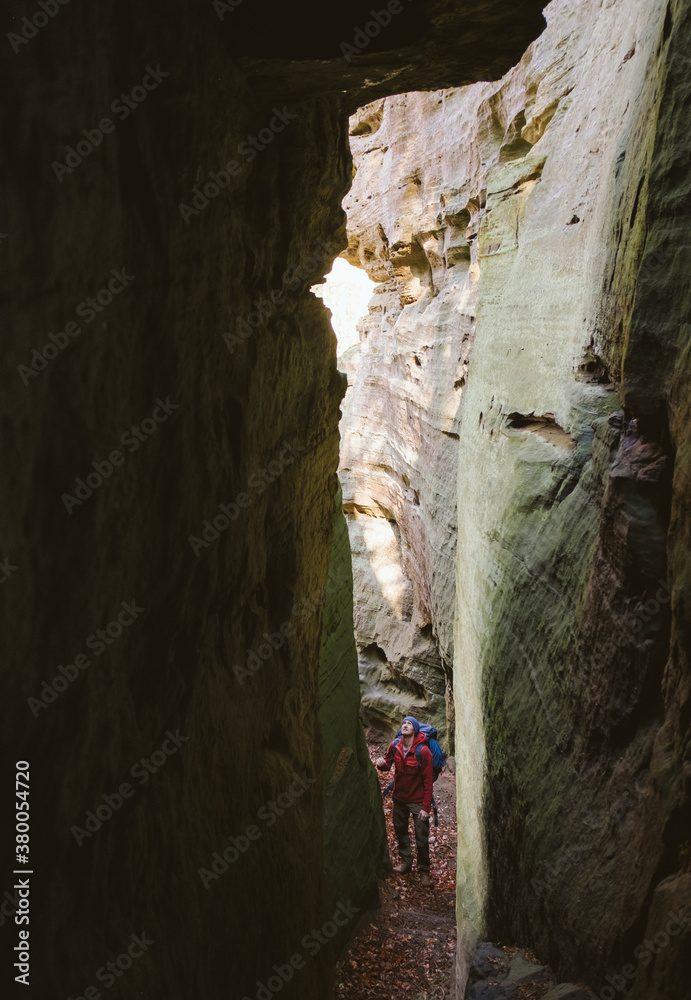 Man standing in a narrow gap between two steep rock walls. Canyon Stock ...