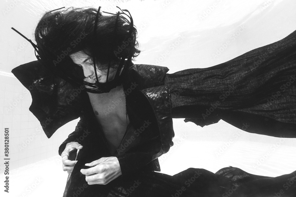 Beautiful man dressed in black floating in the pool Stock Photo | Adobe ...