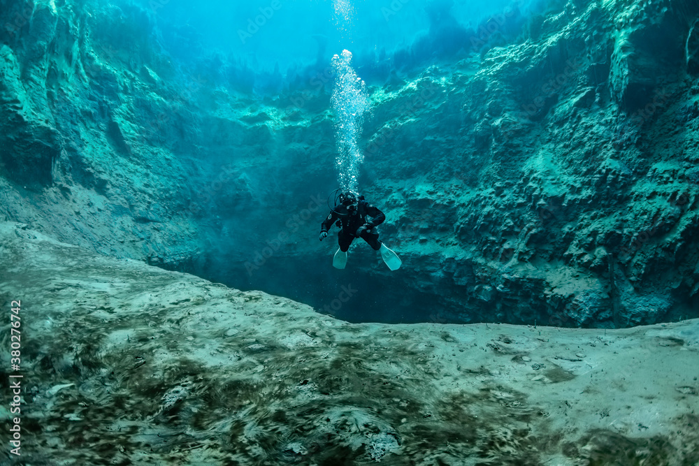 Diver's immersion in a natural funnel with clear water. The water is ...