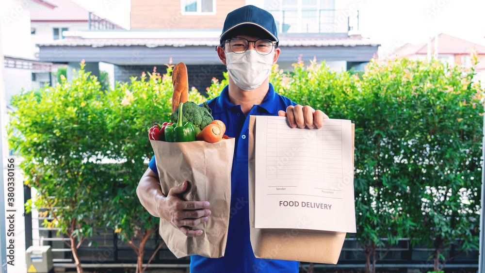 Asian deliver man in uniform with respirator face mask is delivering ...