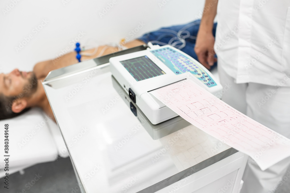 Doctor holding a cardiogram test, close-up of ECG report over a male ...