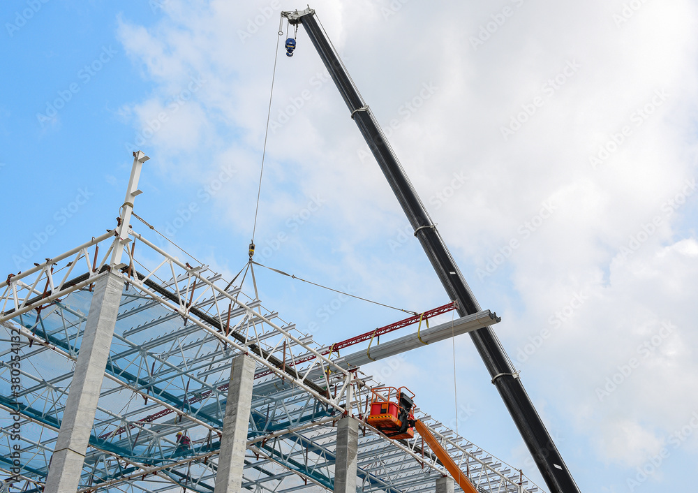 Mobile crane lifting metal roof sheet on palate truss up to stock above ...