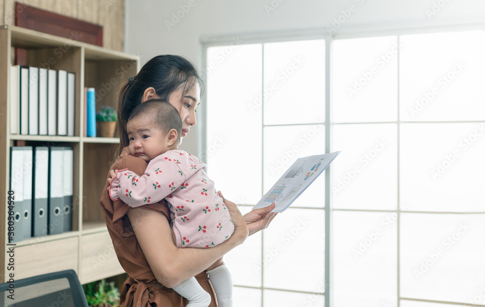 Busy woman trying to work while babysitting newborn baby daughter ...
