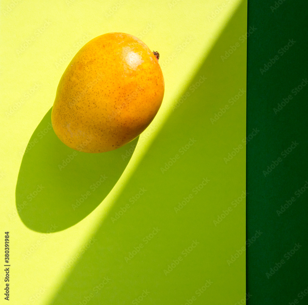 Mango fruit on hard light with shadows, yellow background with green ...