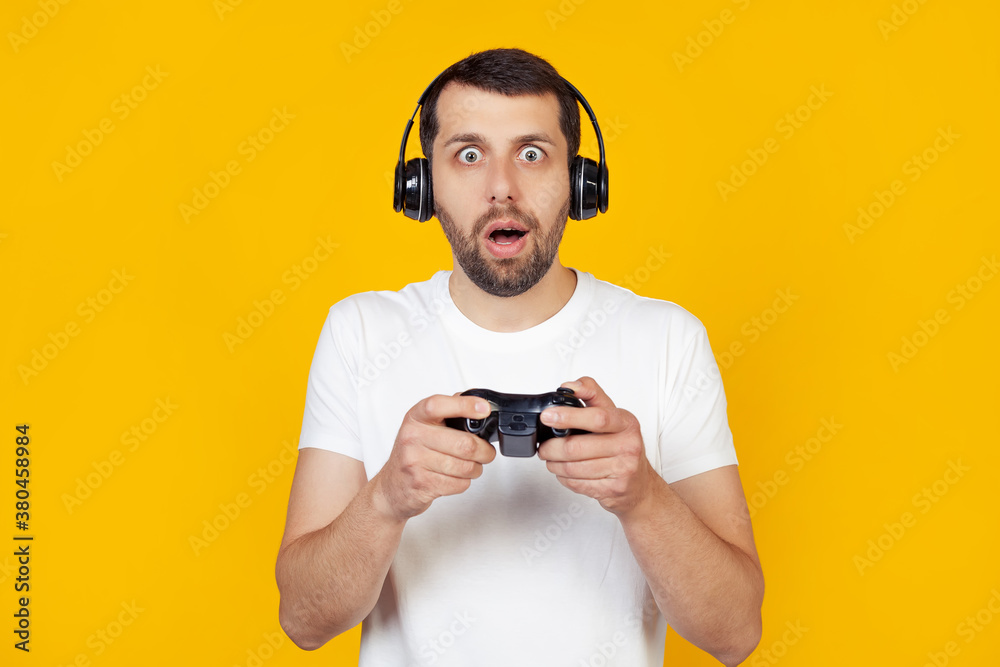 Young man with beard in white t-shirt gamer playing video games with ...