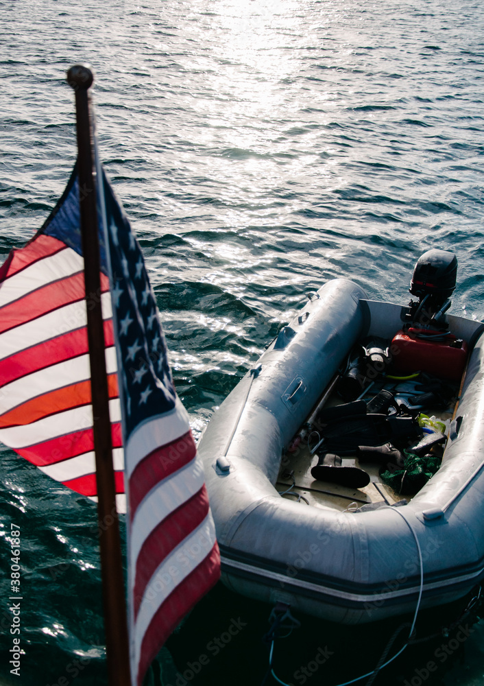 Small inflatable sailing dinghy boat on stern of boat with flag Stock ...
