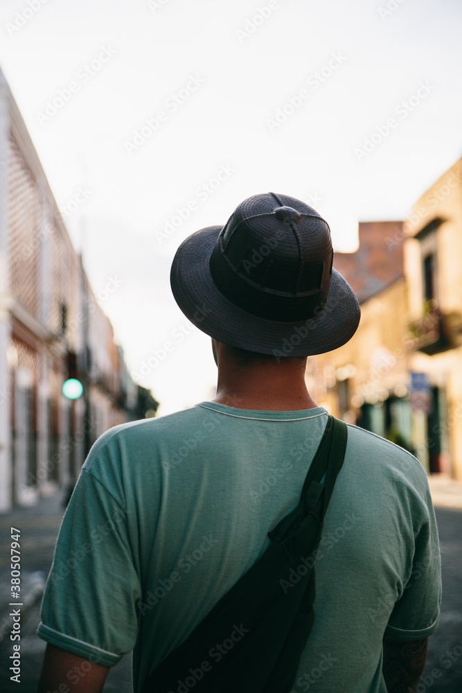 Back view of a man with a hat in the middle of the street between ...