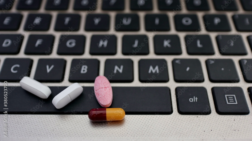 various types of drugs, placed on a laptop keyboard, a symbol of ...